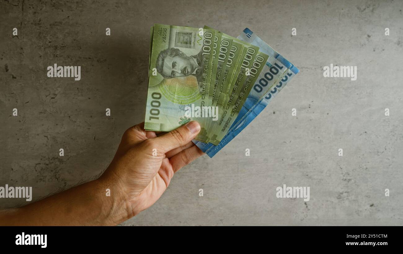 Hand holding chilean pesos against concrete background with different ...