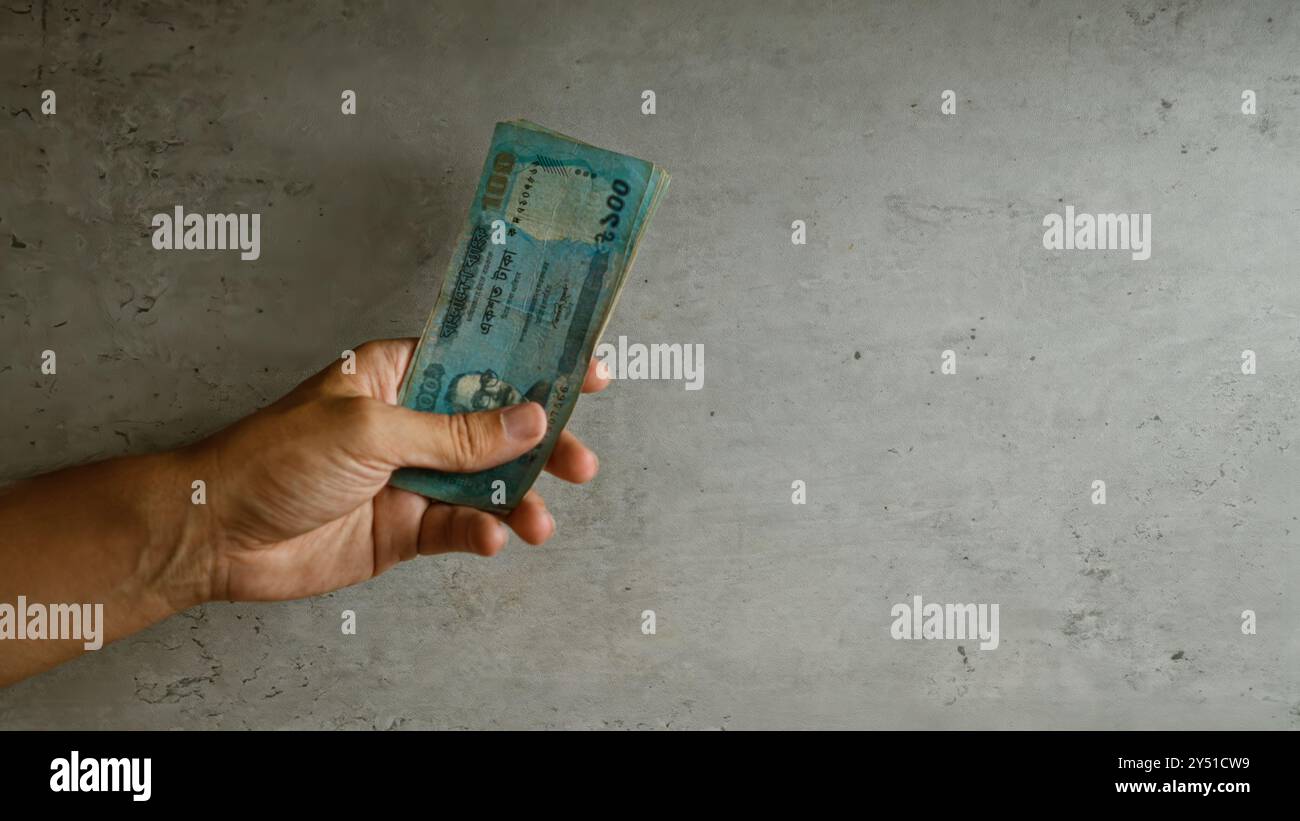Hand holding bangladeshi taka against a concrete background, showcasing ...
