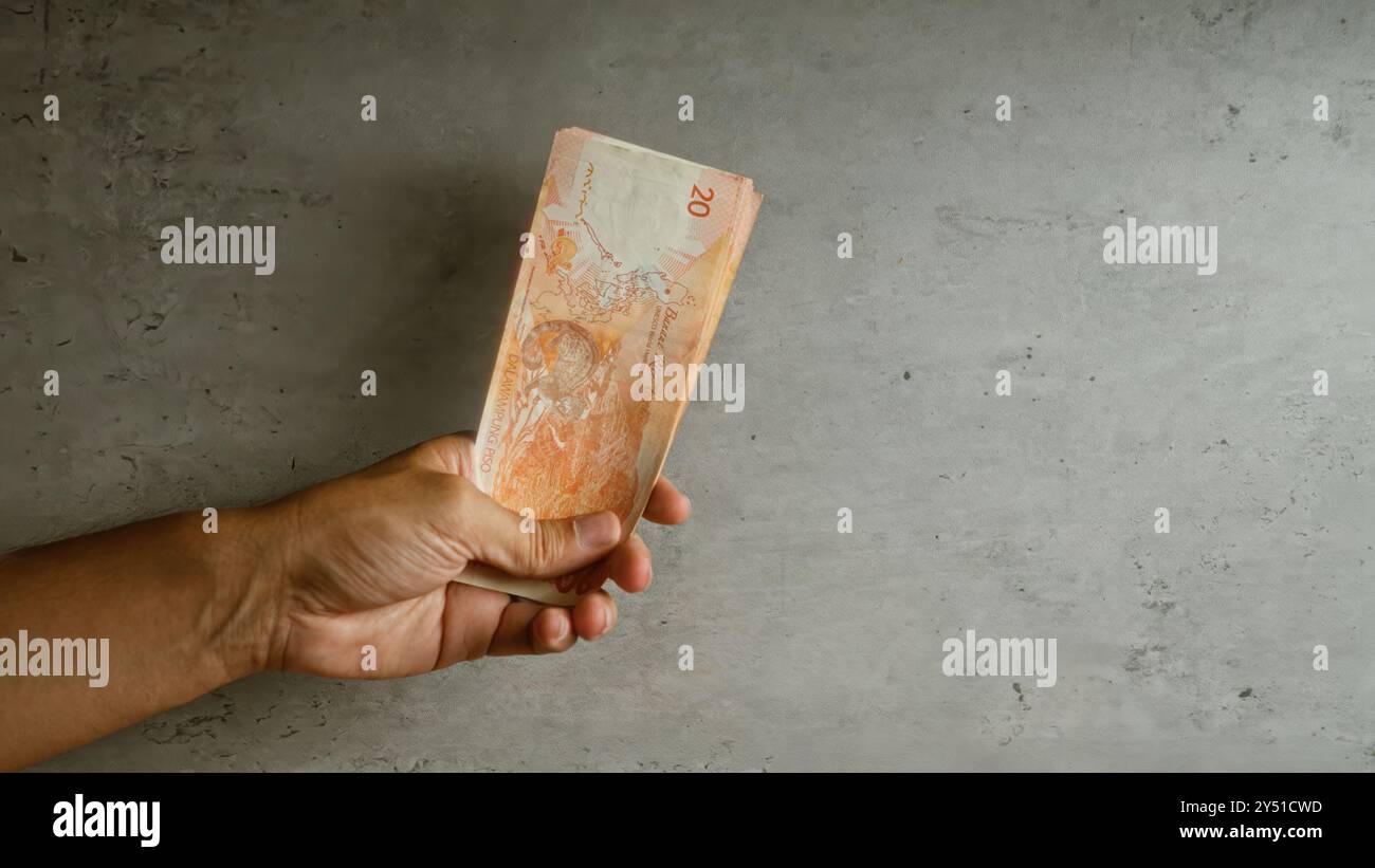 Hand holding philippine peso bills with a concrete background ...