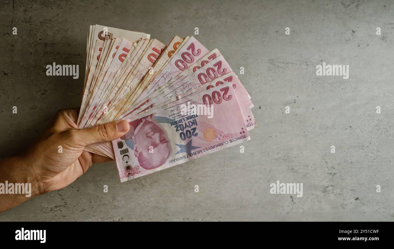 Hand holding turkish lira bills against a concrete background ...