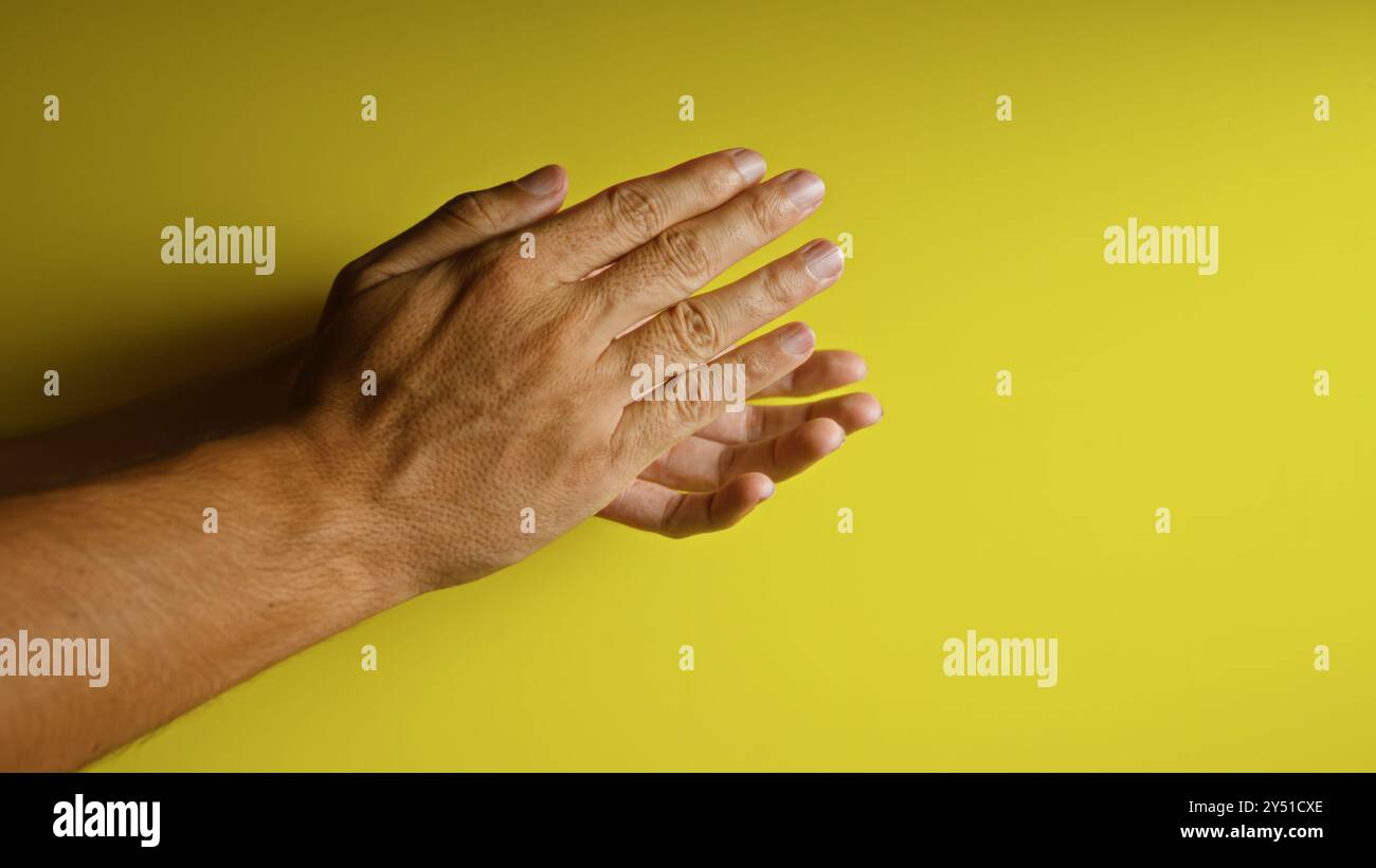 Man clapping hands against a bright yellow background, showcasing ...