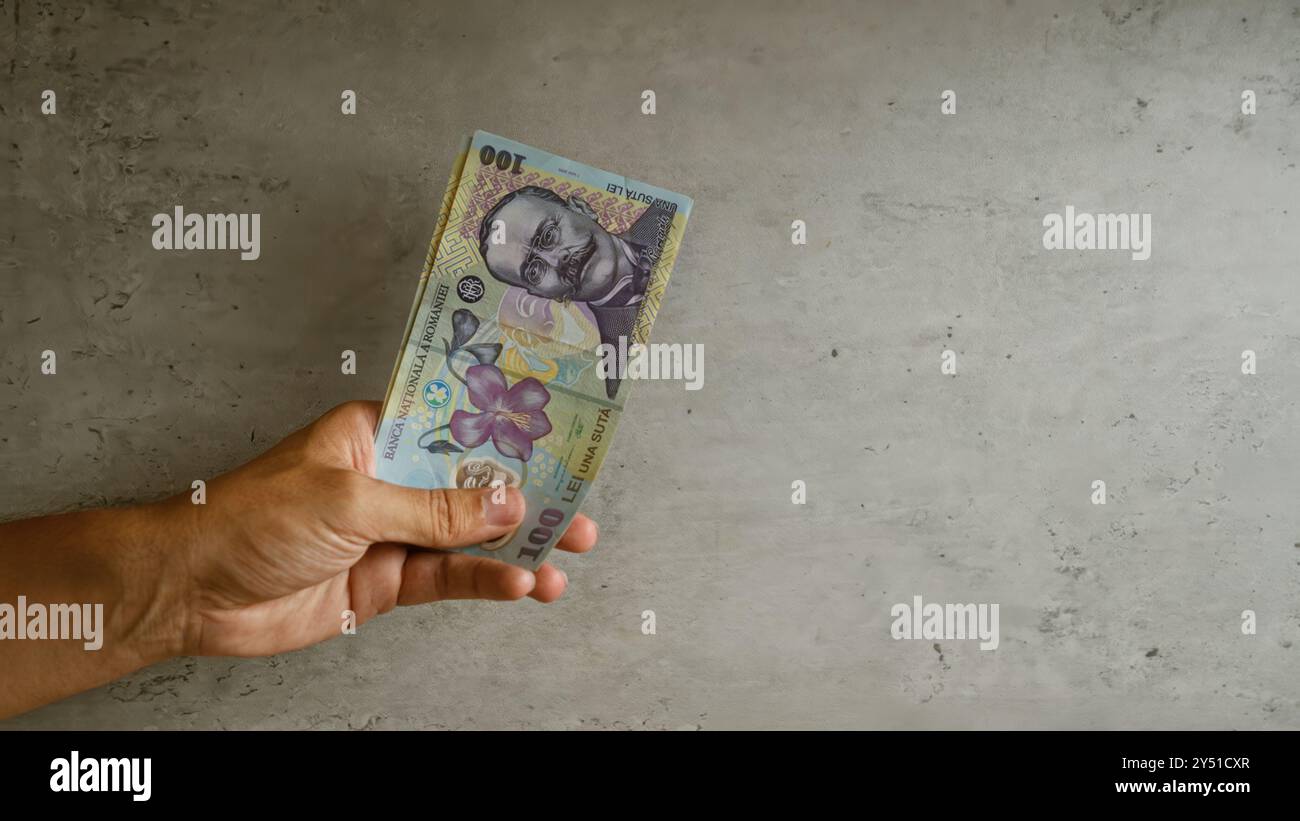 Hand holding romanian lei against a concrete background, capturing the ...
