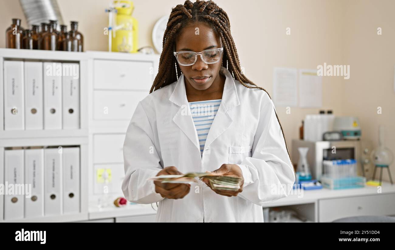 African american woman with braids counts currency in a lab, wearing a ...