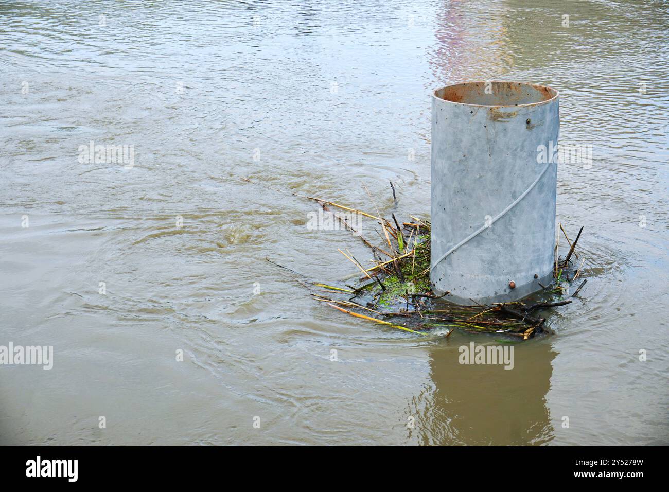 Cylindrical metal object, pipe or barrier, partially submerged in water ...