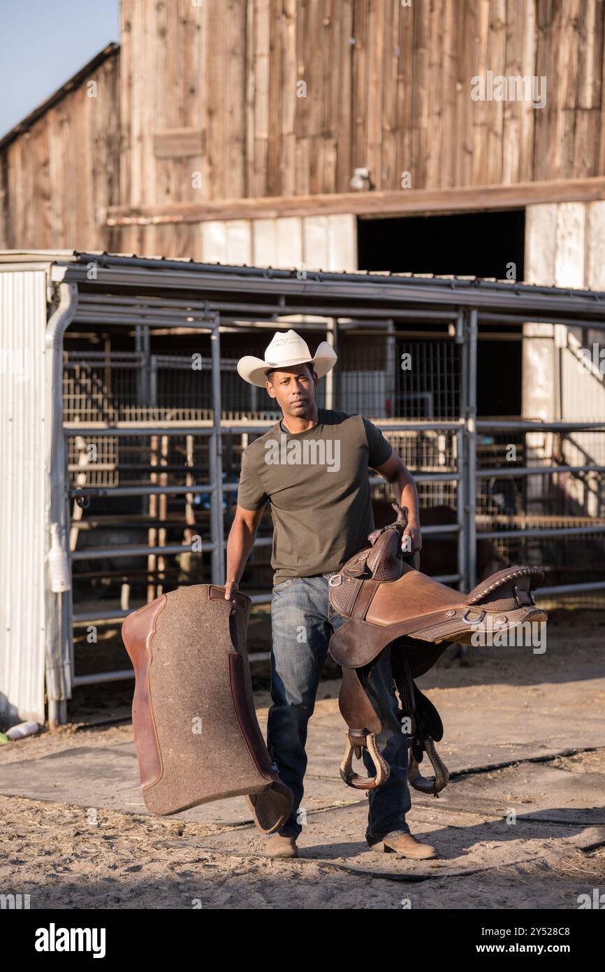 Man holding a heavy saddle looking at camera Stock Photo - Alamy