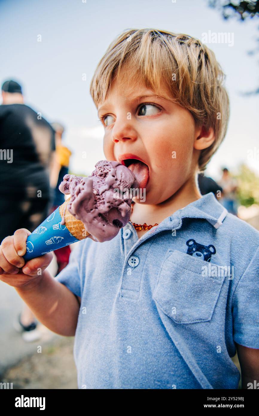 A young boy licking his ice cream cone, enjoying the treat Stock Photo - Alamy