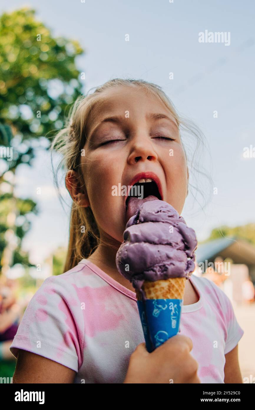 A young girl enthusiastically licking a large ice cream cone Stock ...