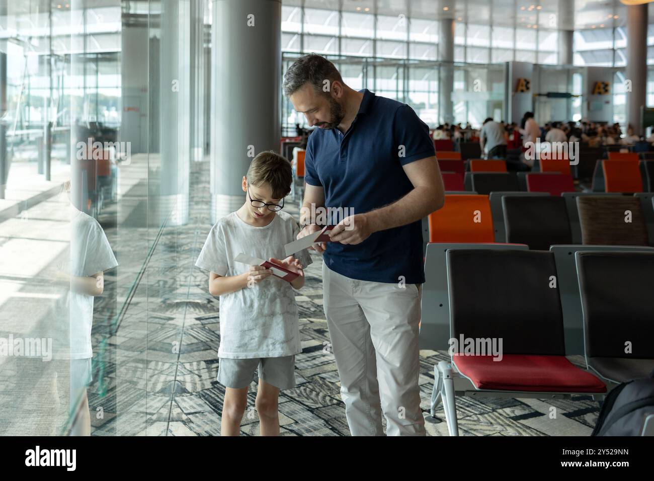 Dad and his son are looking at the plane tickets in terminal Stock ...