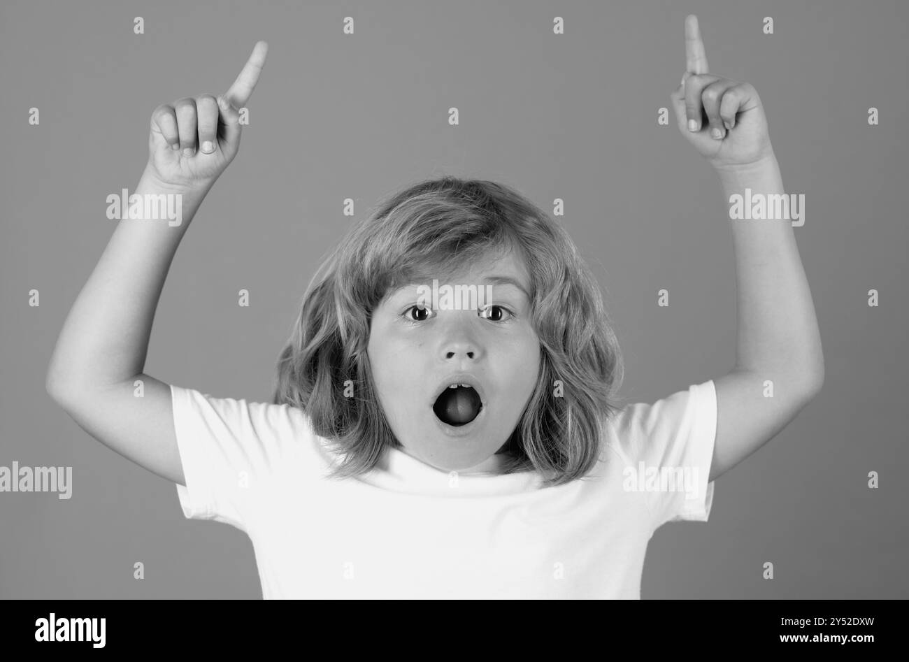 Surprised child pointing up finger on studio background. Shocked kid ...