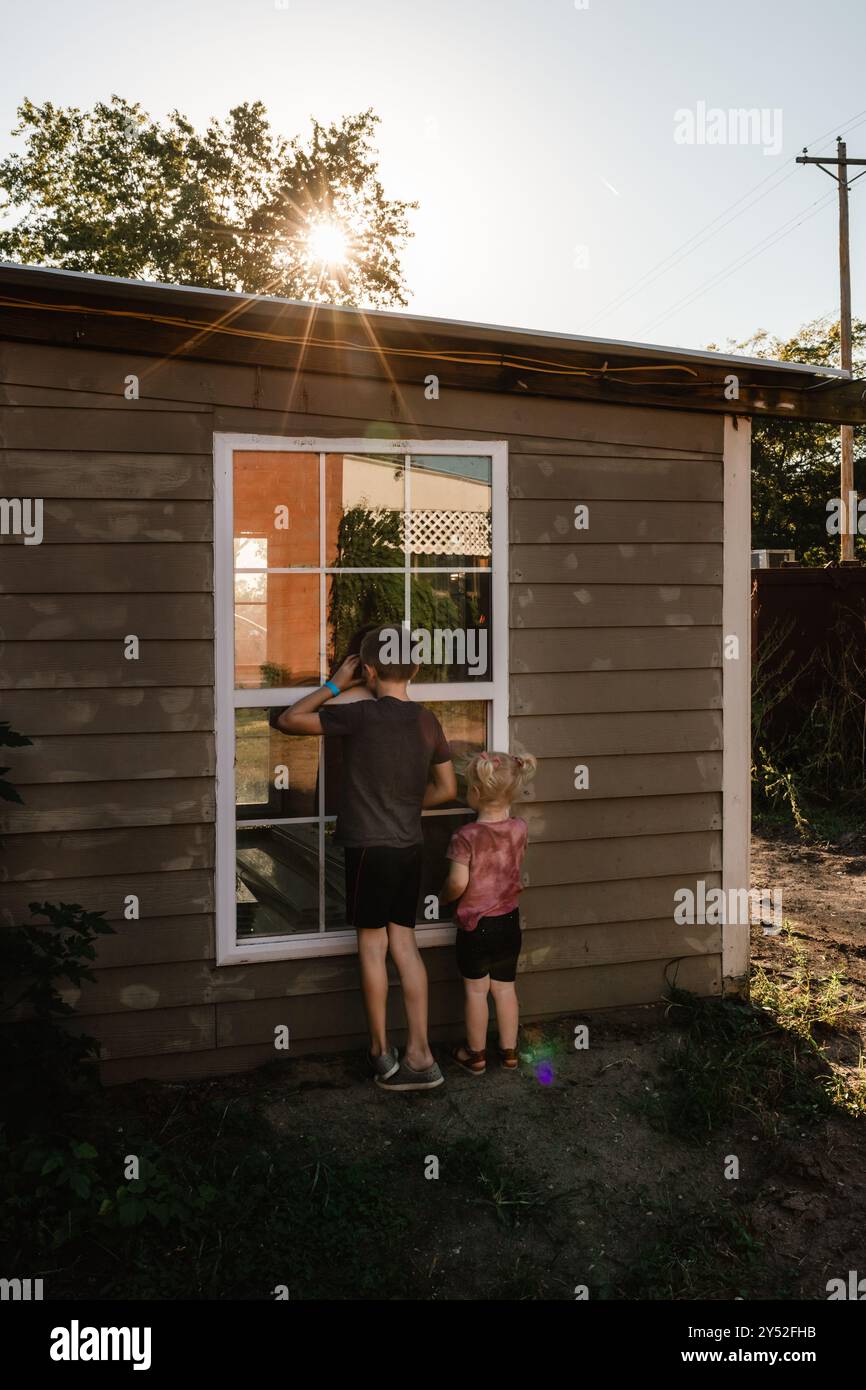 Kids peeking into window on house at golden hour Stock Photo - Alamy