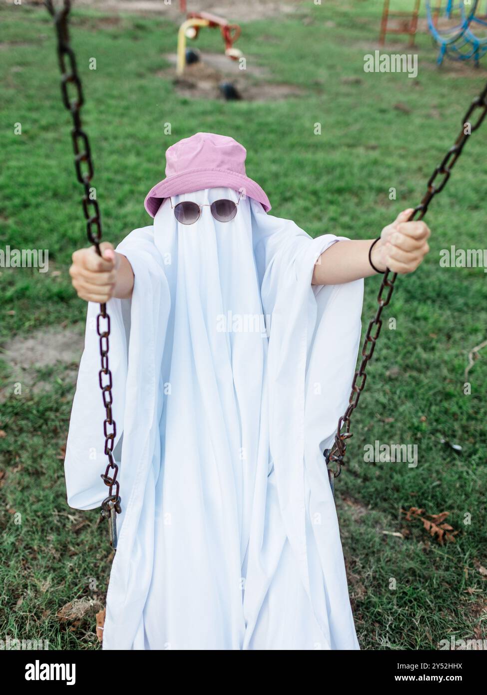 Sheet ghost on playground swing Stock Photo - Alamy
