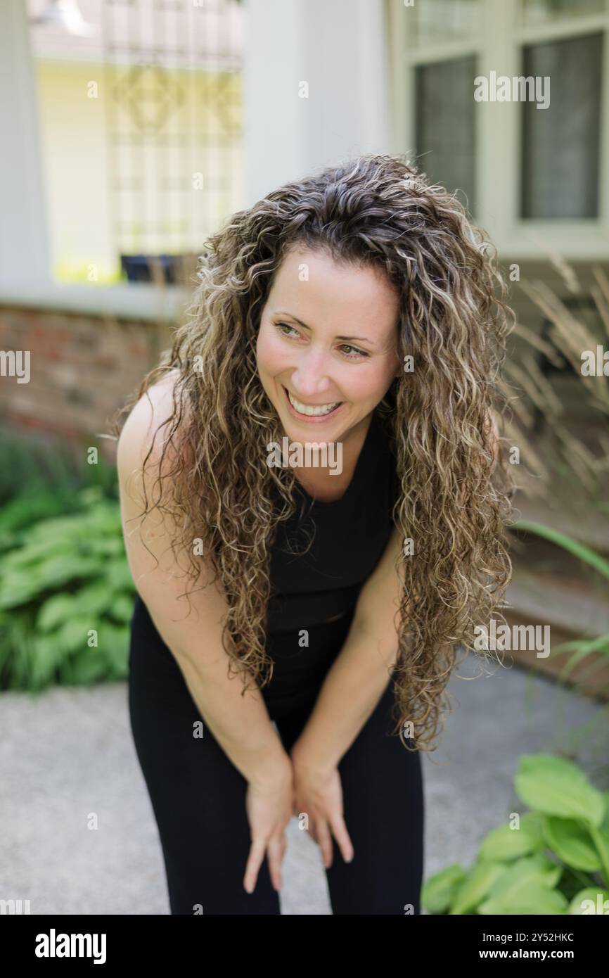 Healthy young woman leaning forward, laughing outside of home Stock ...