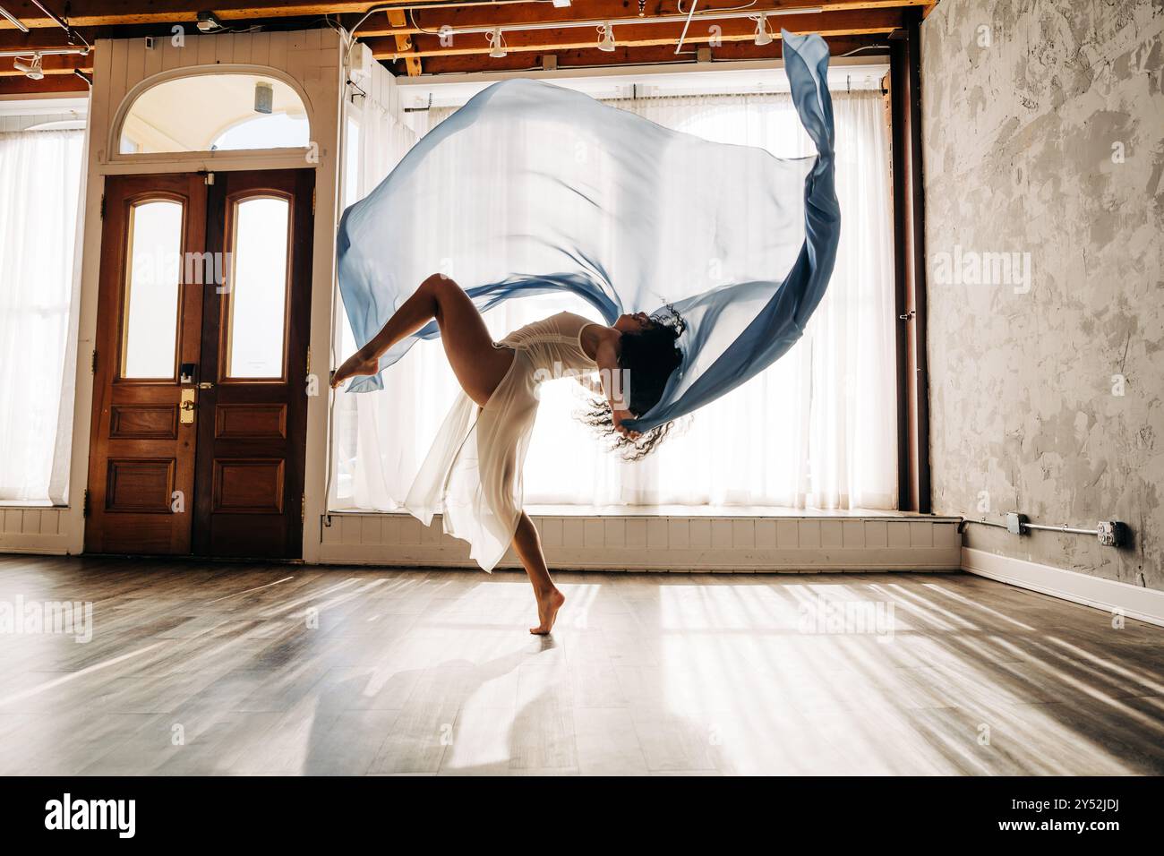 Ballet dancer with flowing blue fabric, performing a graceful movement ...