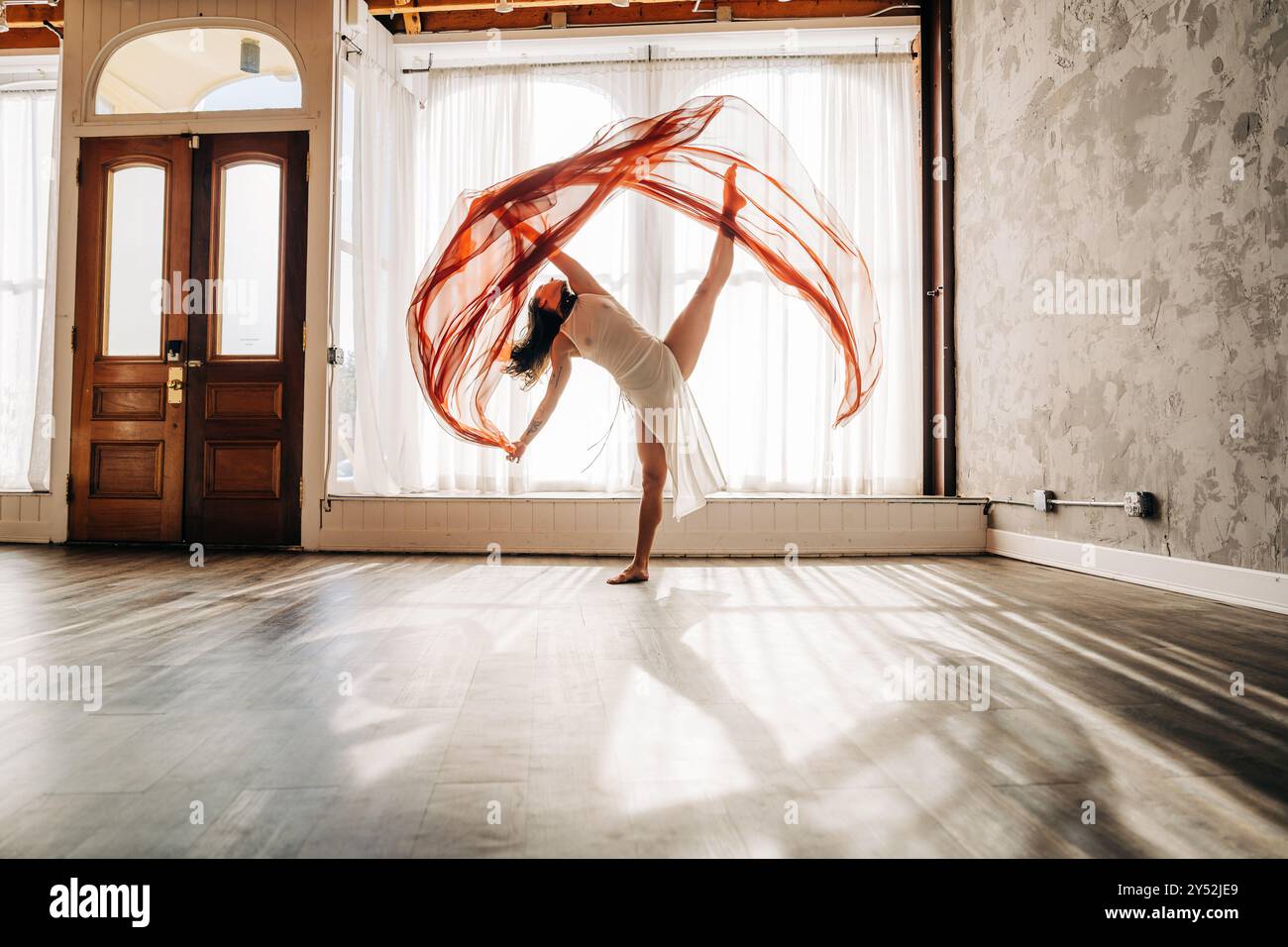 Ballet dancer with flowing red fabric, gracefully extending leg Stock ...