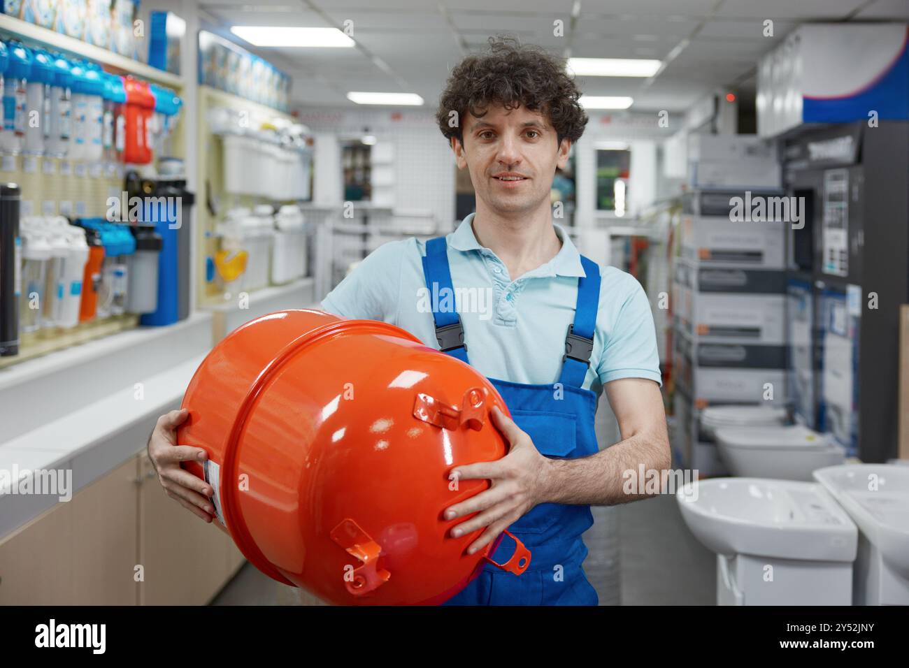 Portrait of plumber carrying hydraulic tank bought at plumbing shop ...