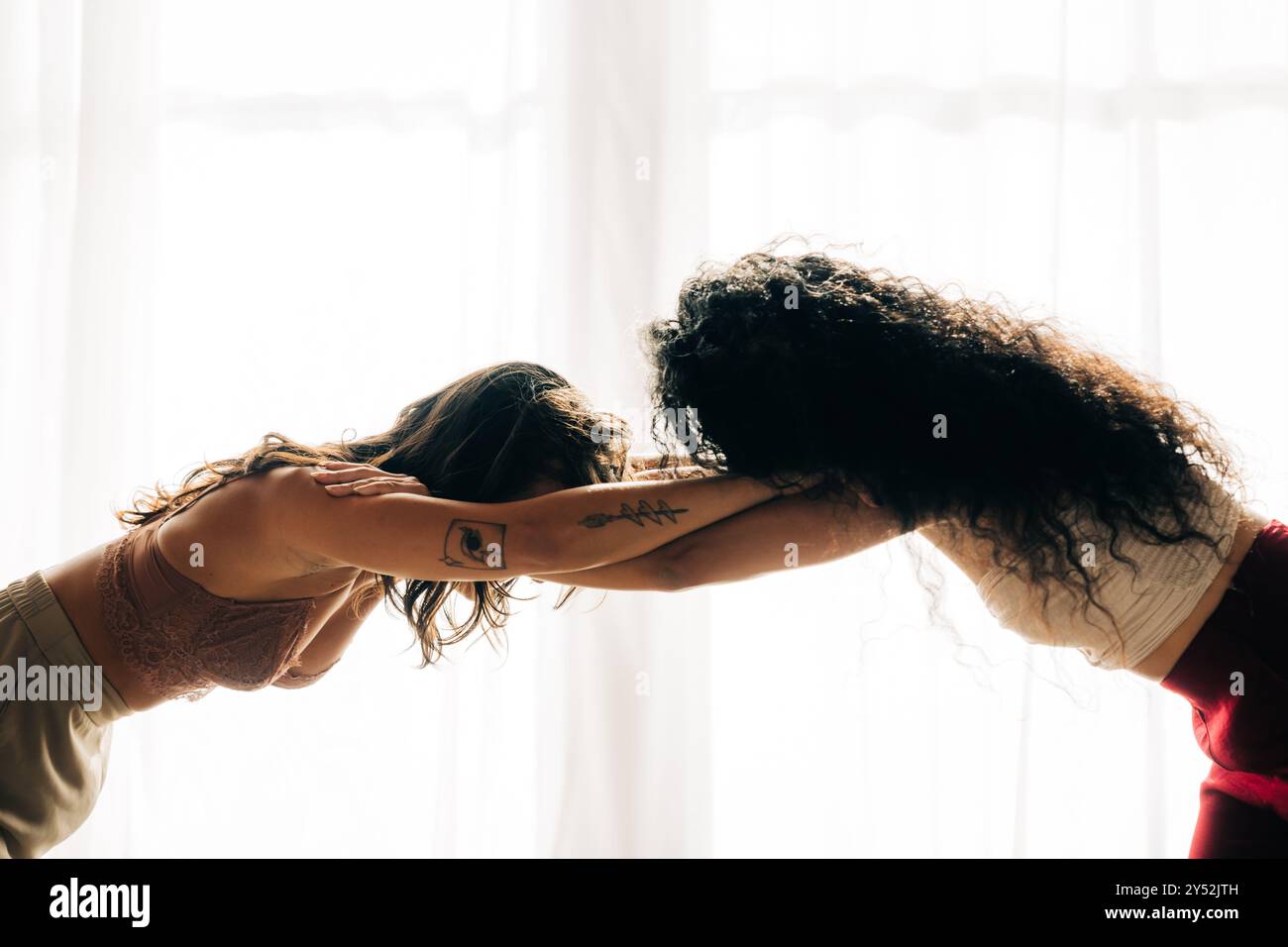 Two women lean forward, in a graceful, supportive gesture Stock Photo ...