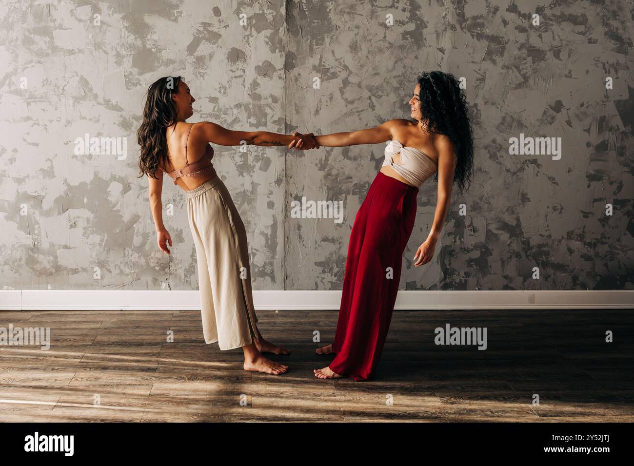 Two women holding hands and playfully leaning back Stock Photo - Alamy