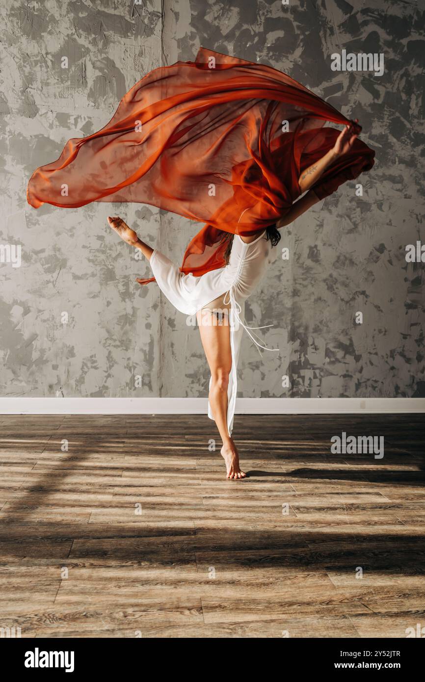 Ballet dancer with flowing red fabric gracefully kicking leg Stock ...