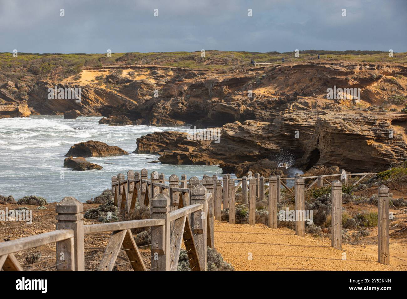 Coastal path winding along cliffs with rugged rocks and wooden railing ...