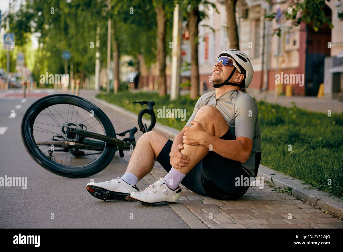 Bicyclist holding injured leg after falling from bicycle having ...