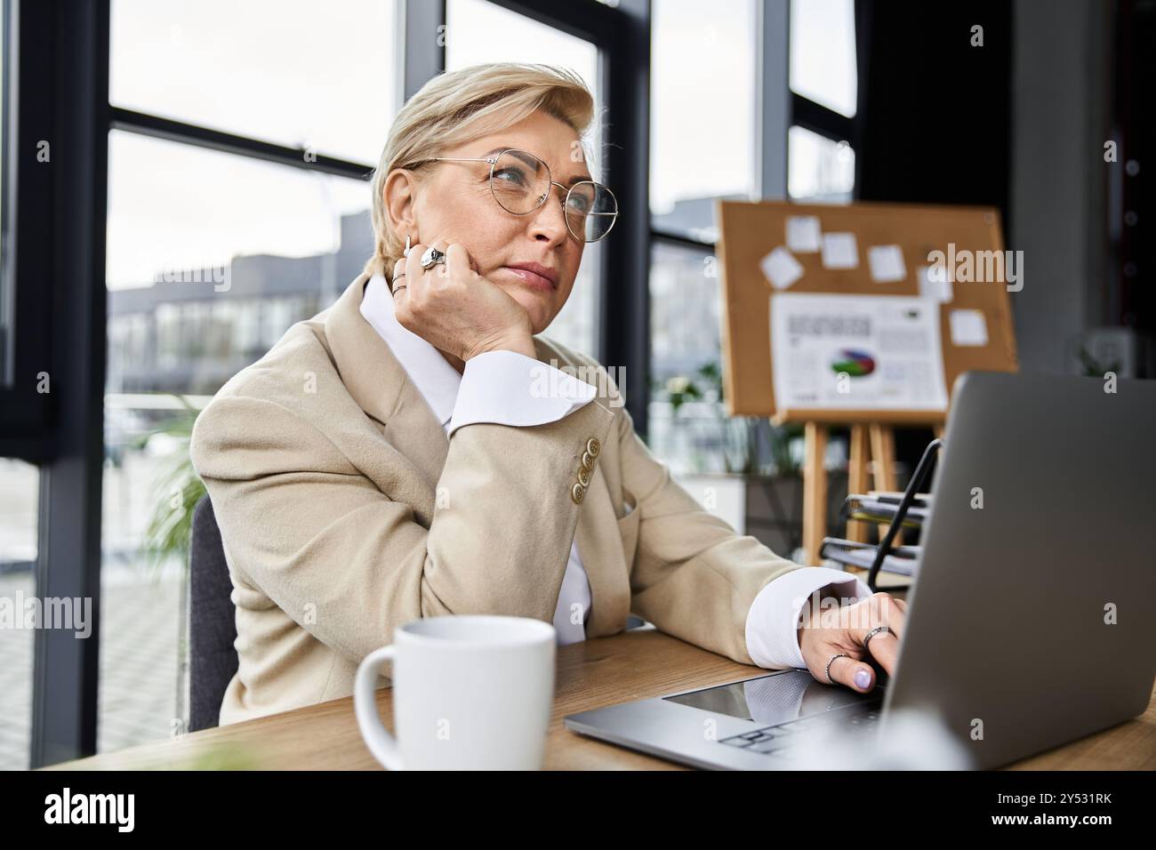 A fashionable woman reflects while working intently at her contemporary ...