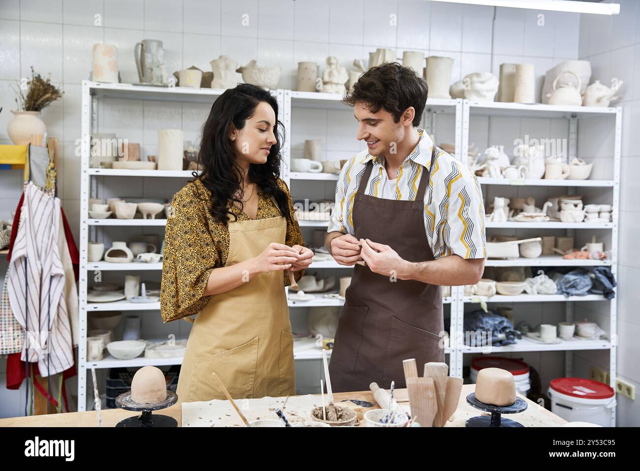 A couple shares a joyful moment while crafting pottery side by side ...