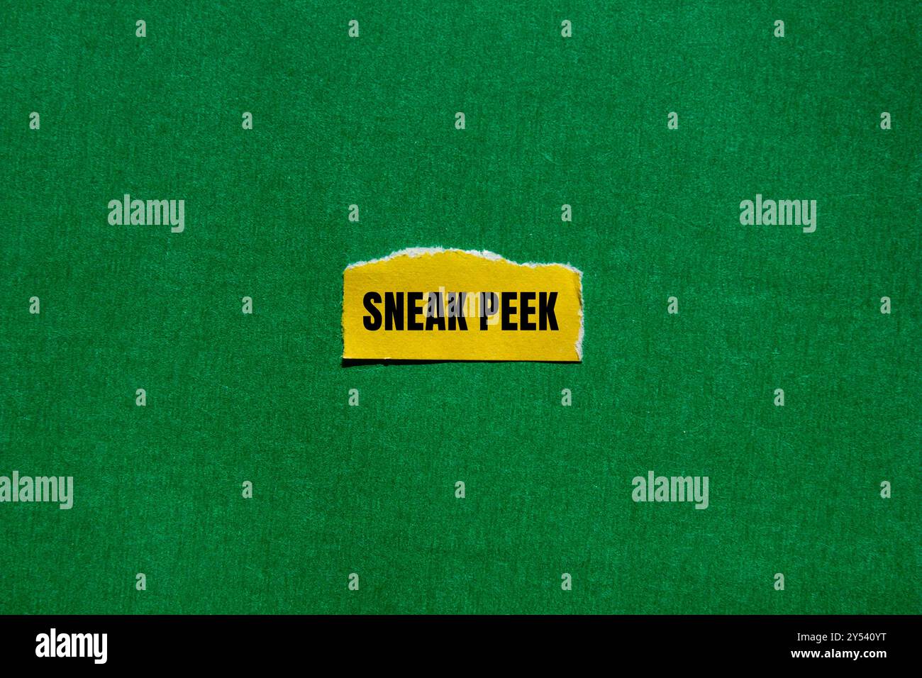 Sneak peek message written on ripped torn yellow paper piece with green ...