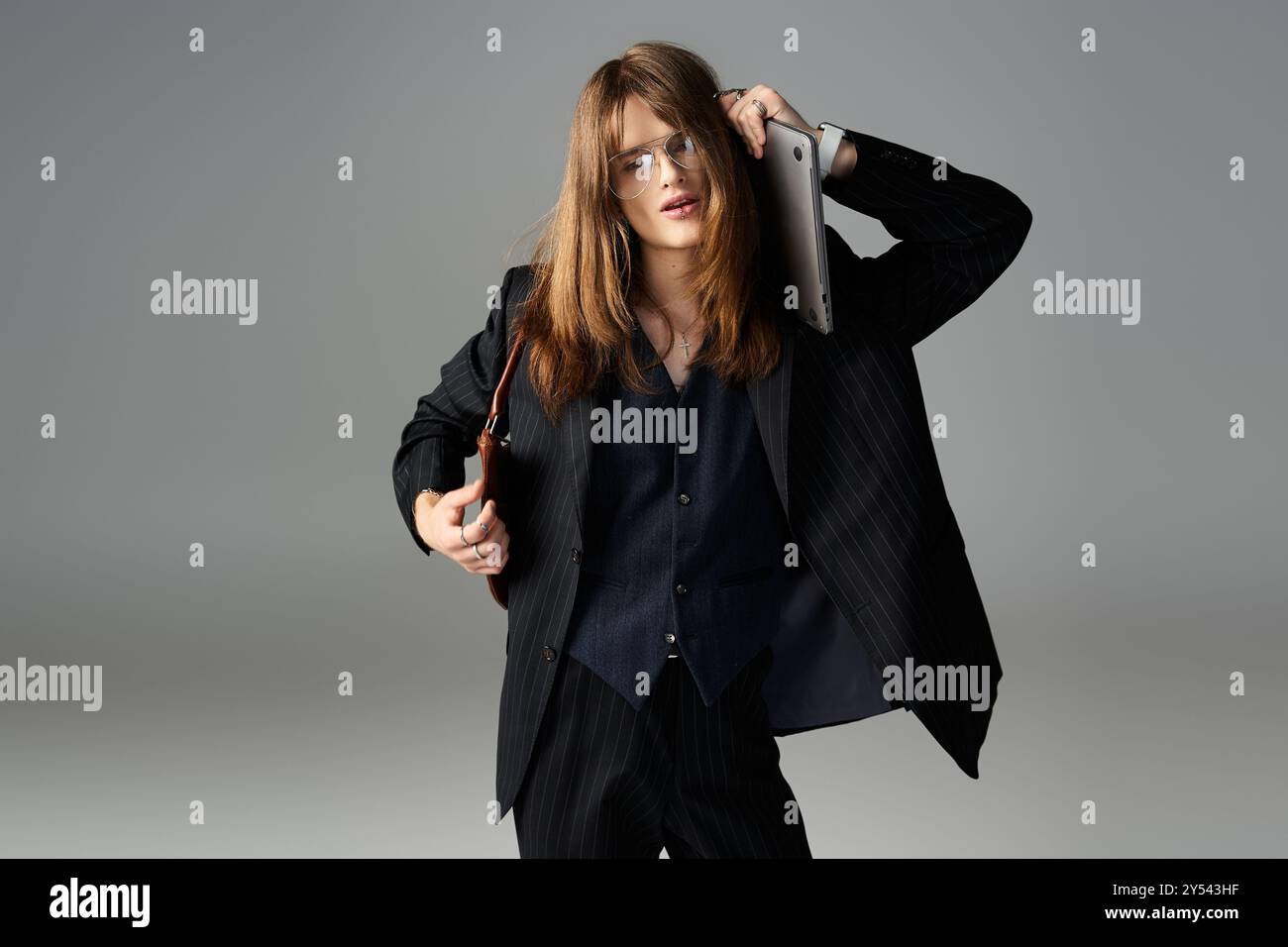 A young man in fashionable attire strikes a dynamic pose, showcasing ...
