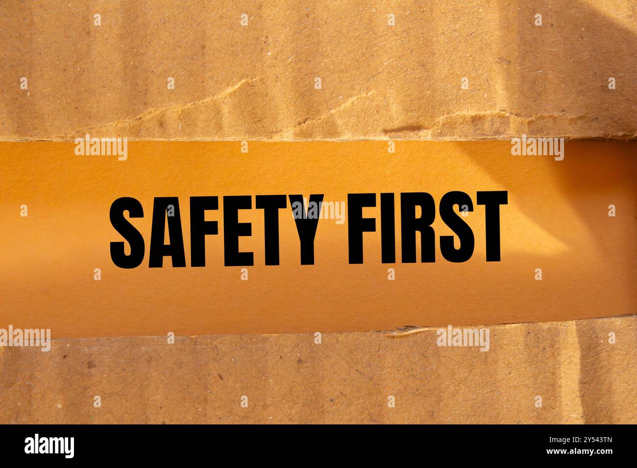 Safety first message written on ripped torn cardboard paper with orange ...