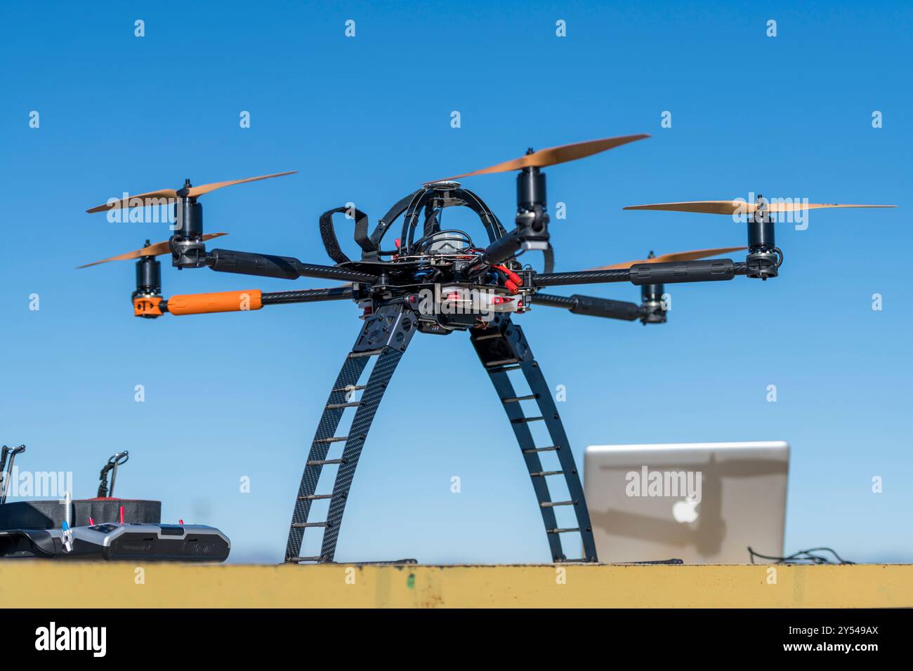 A large drone with six propellers is sitting on a ladder. The drone is ...
