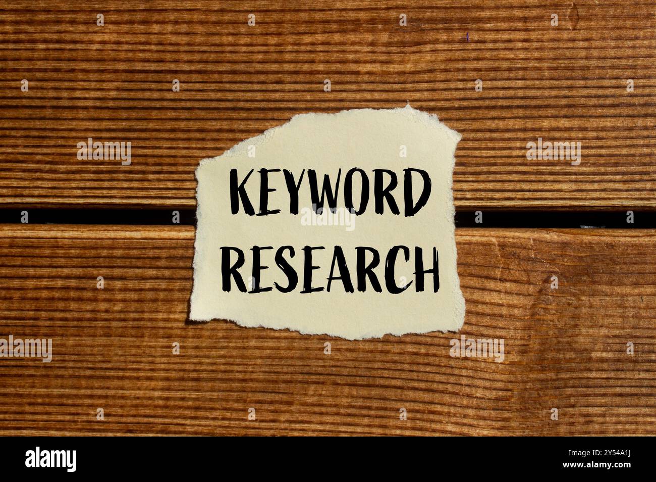 Keyword research message written on ripped torn paper with wooden ...
