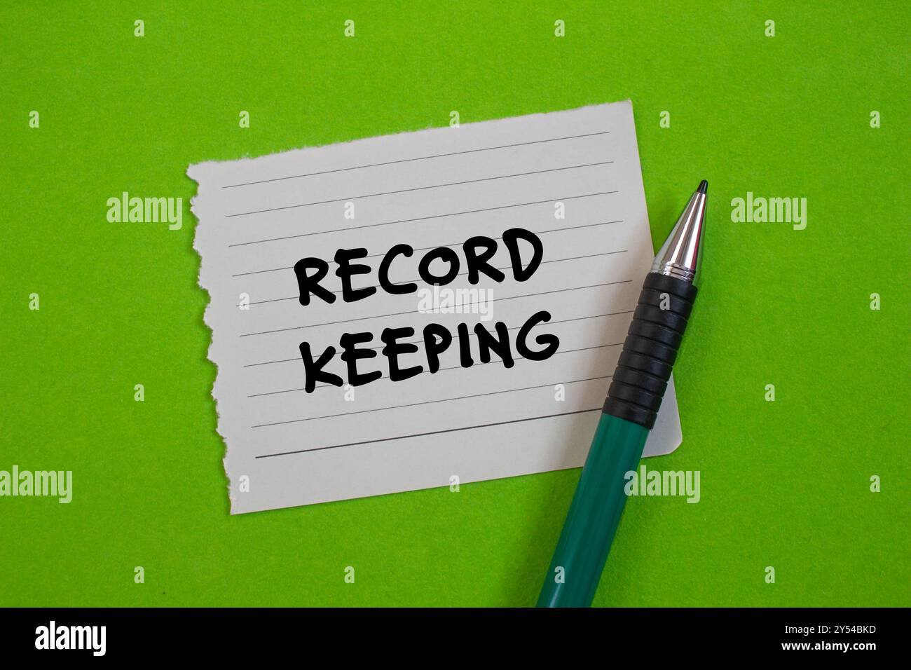 Record keeping message written on ripped torn paper with a pen on green background. Conceptual ...