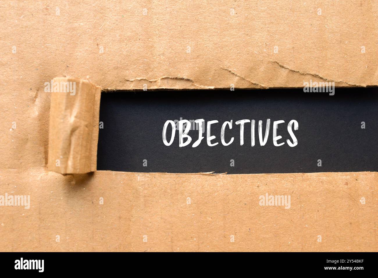 Objectives message written on ripped torn cardboard paper with black background. Conceptual ...