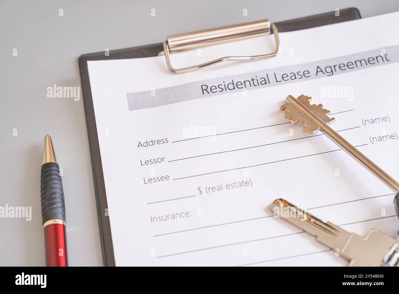 Residential lease agreement with keys and pen on clipboard signifying ...