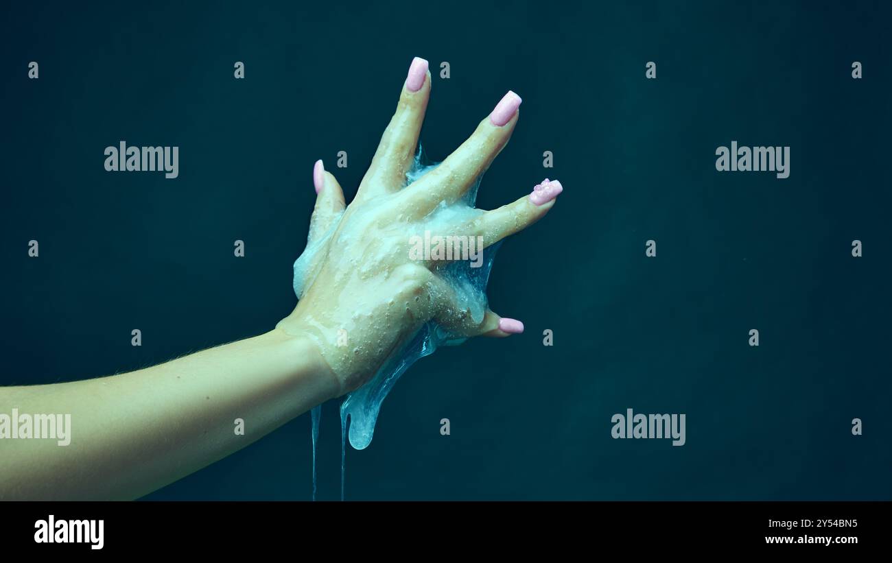 Female hand covered in slime, gesturing against cyan green background ...