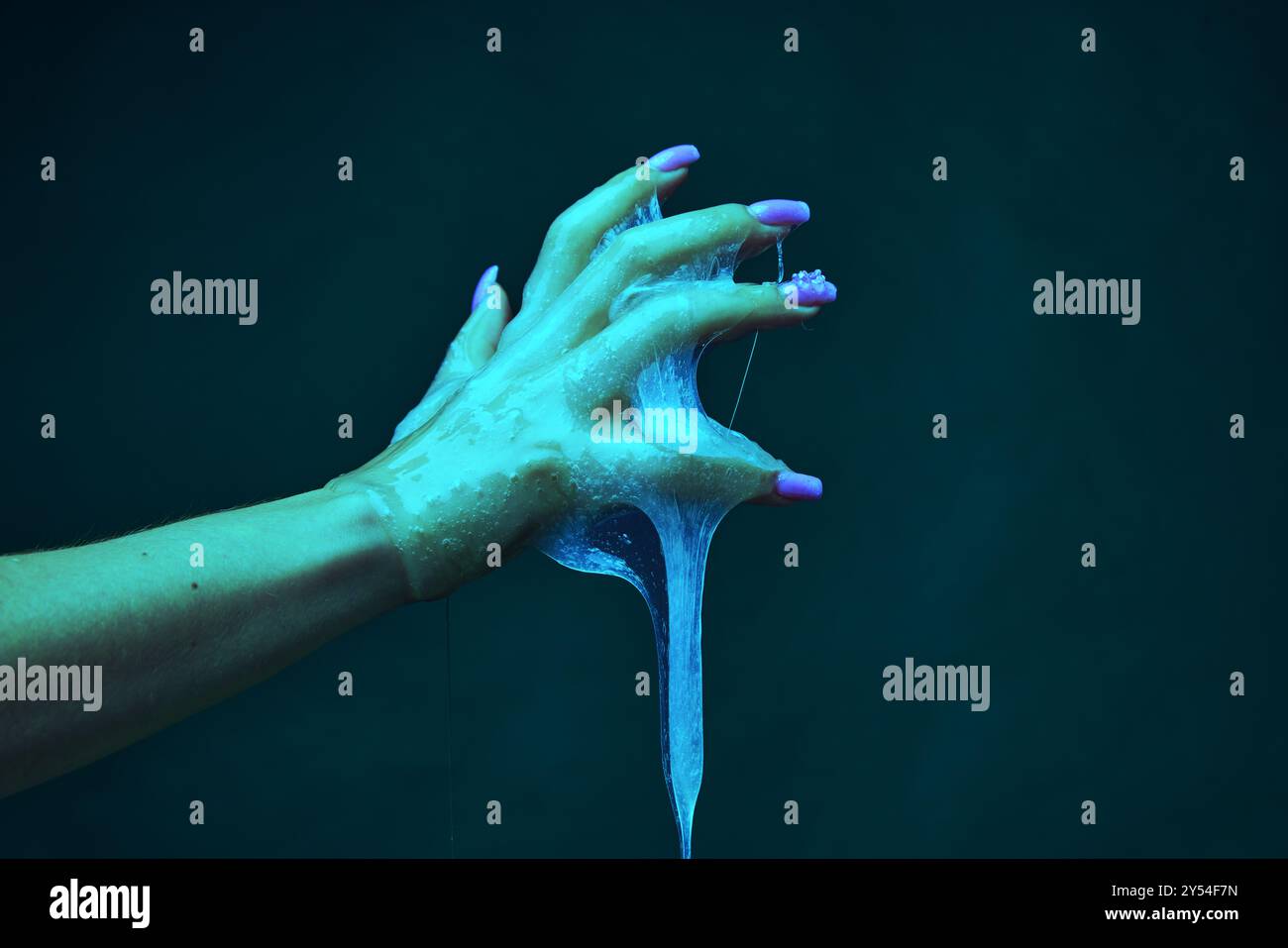 Female hand covered in slime, gesturing against cyan green background ...