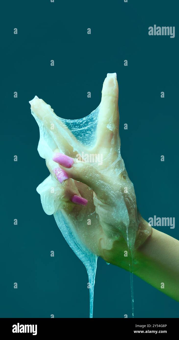Female hand covered in slime, gesturing against cyan green background ...