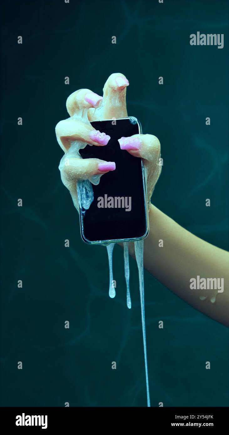 Female hand covered in slime, holding mobile phone against cyan green ...