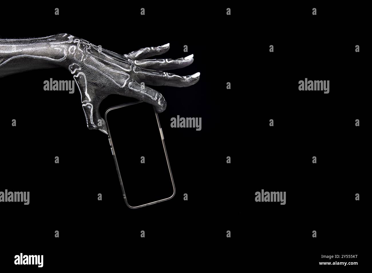 Skeleton hand holding mobile phone with blank screen against black ...