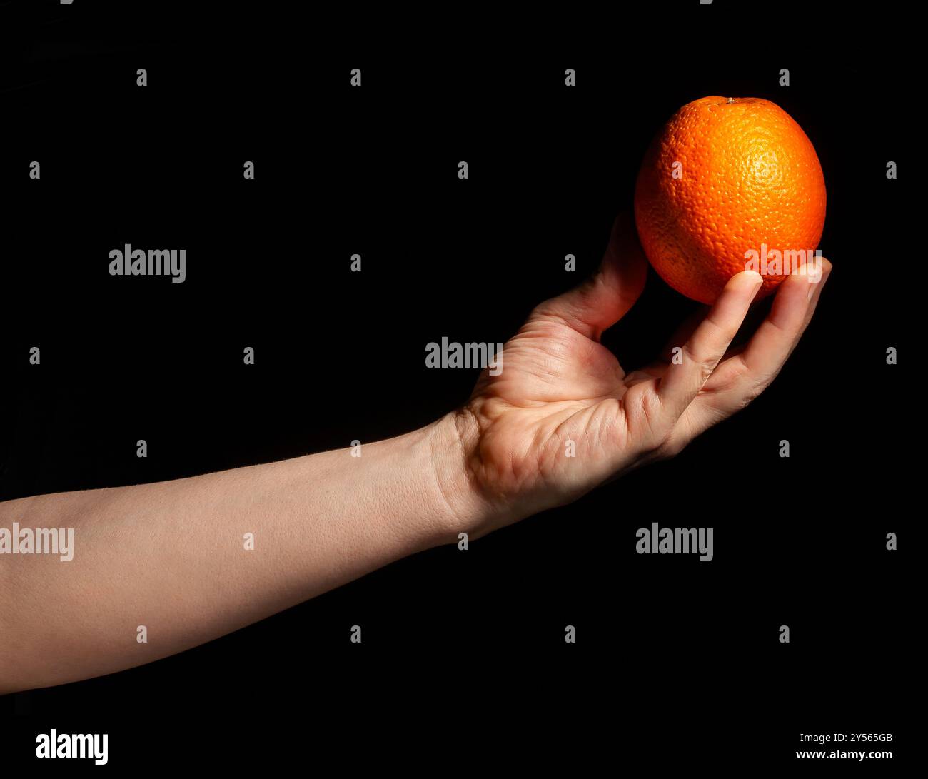 orange in hand on black background Stock Photo - Alamy
