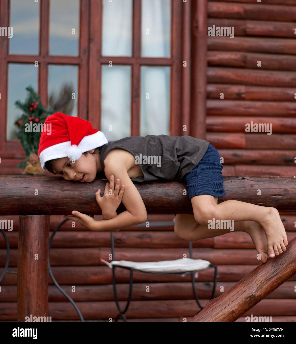 latin boy holds himself leaning back hugging the trunk of a balcony of ...