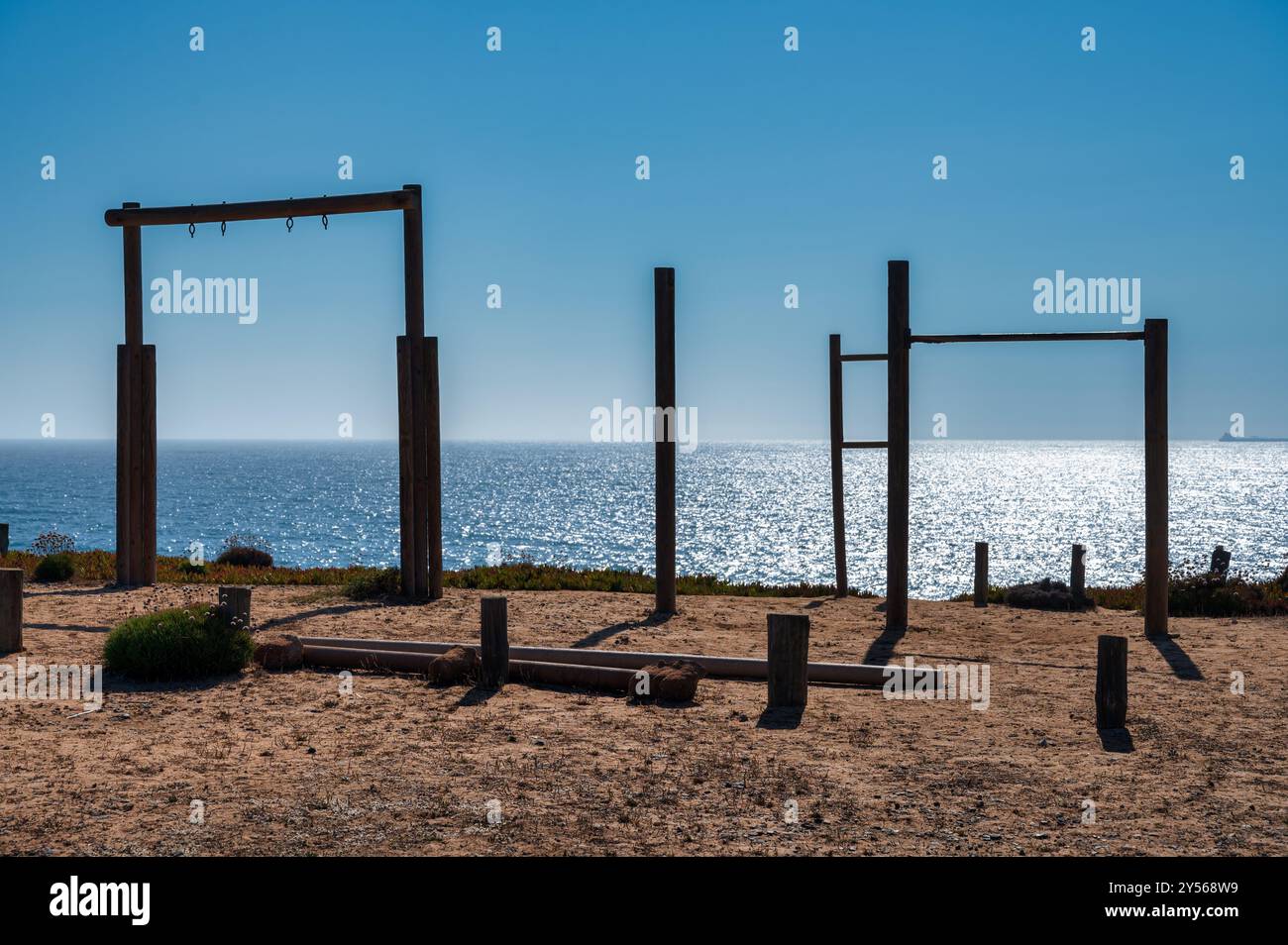 Rustic wooden fitness equipment overlooking the ocean under a clear ...