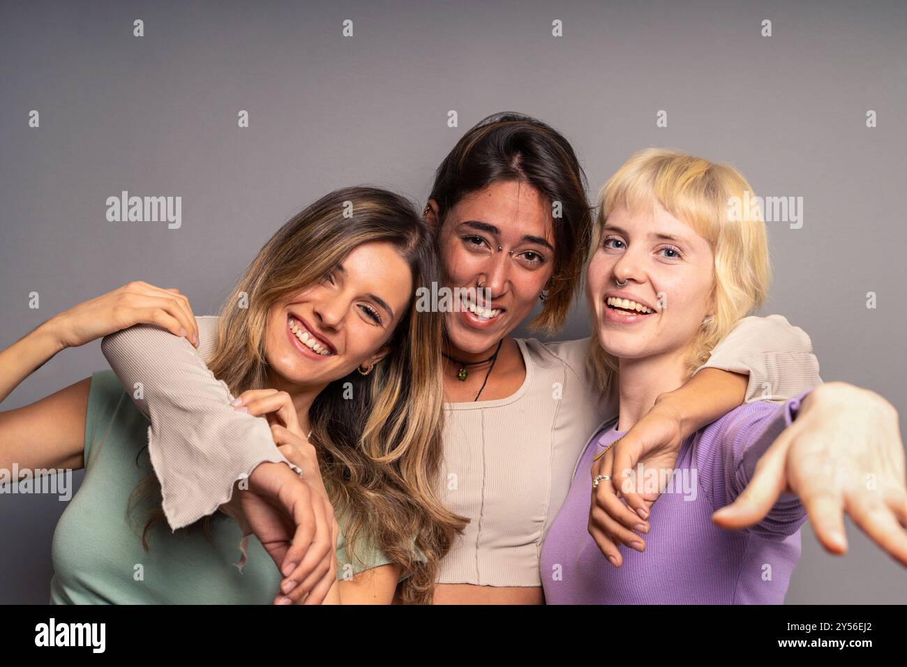Diverse young women friends embracing and laughing together against a ...