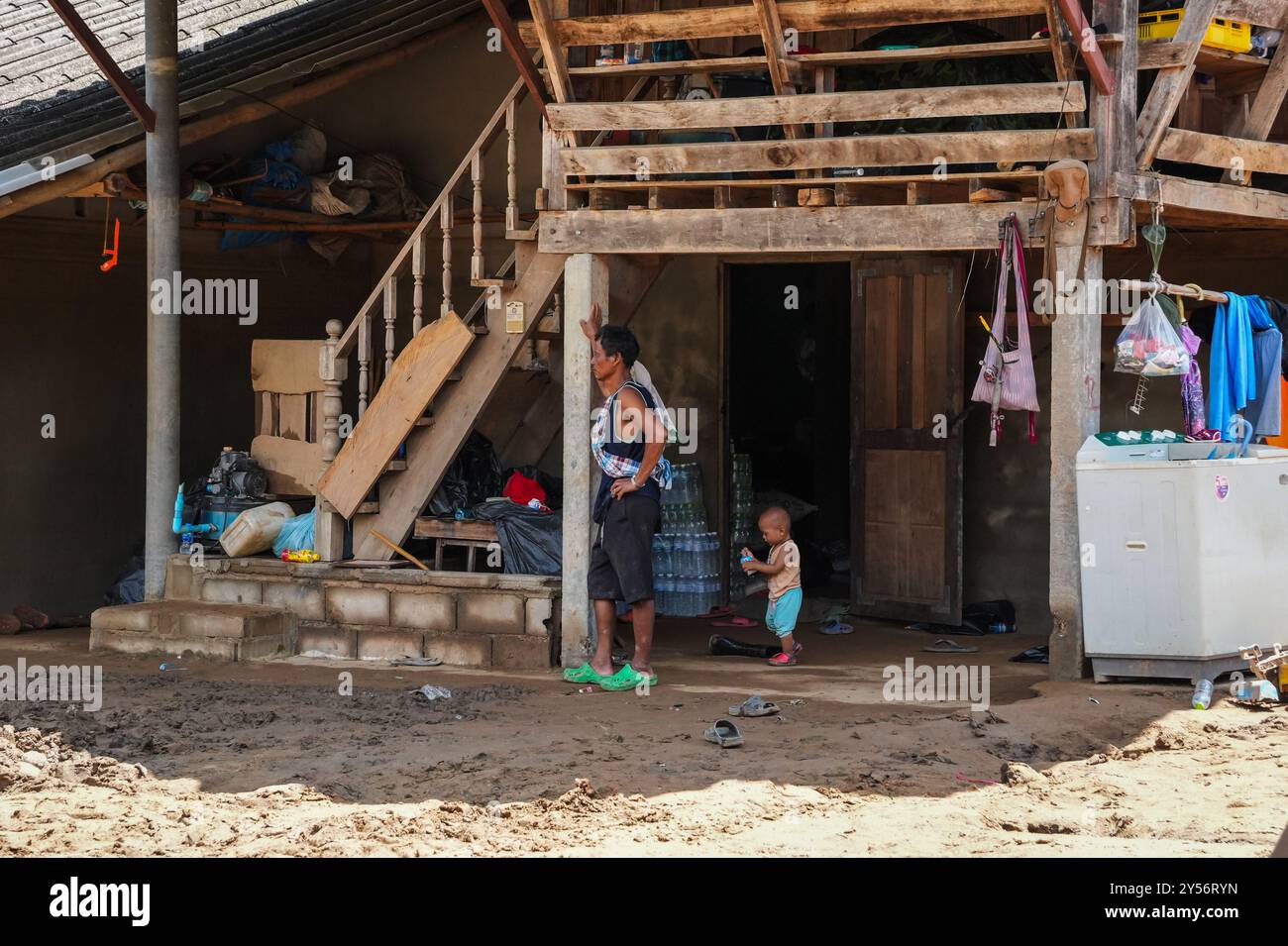 A man with his kid is seen standing in front of her house surrounded by ...
