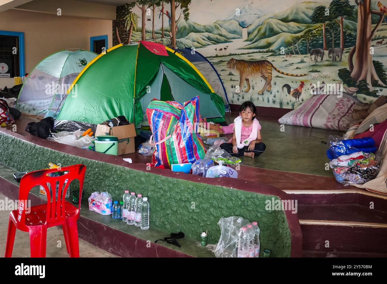 Chiang Rai, Thailand. 17th Sep, 2024. A kid is seen sitting near her ...