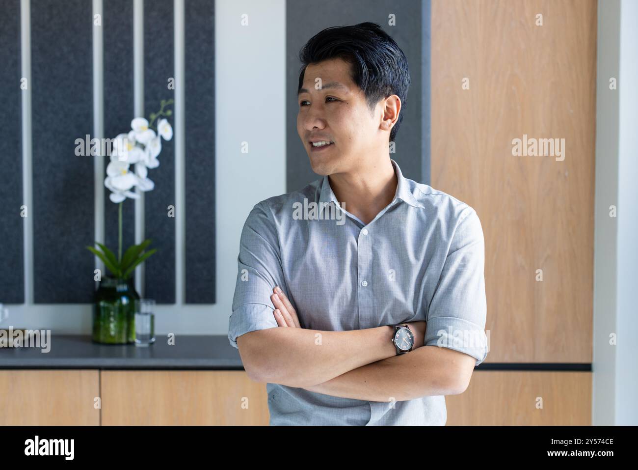 Confident asian man standing with arms crossed in modern office space ...