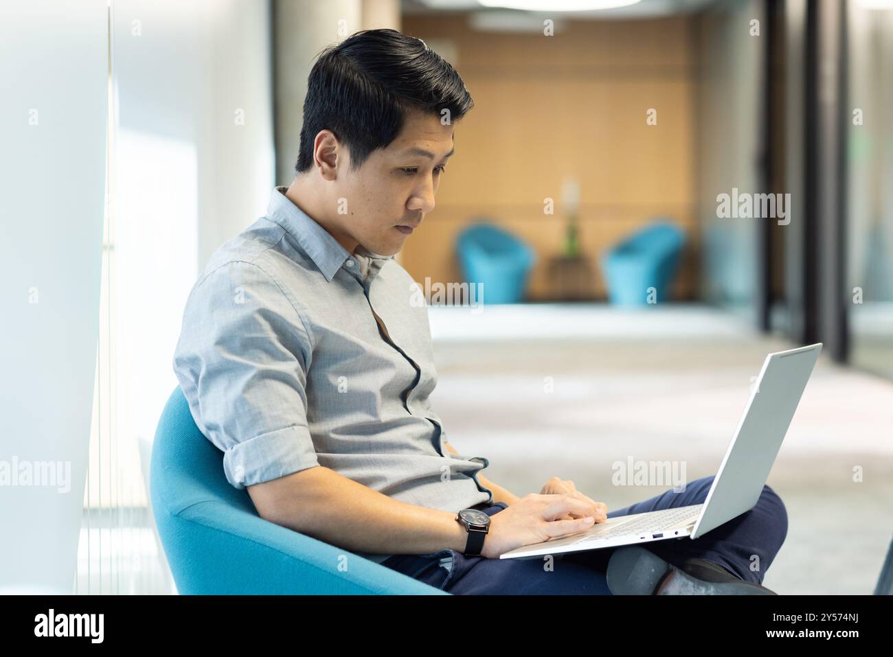 Working on laptop, asian man focusing on business tasks in modern ...