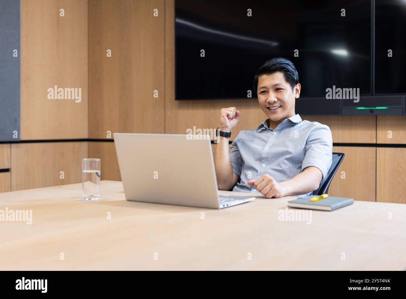 Celebrating success, asian man sitting at desk with laptop in modern office. celebration ...