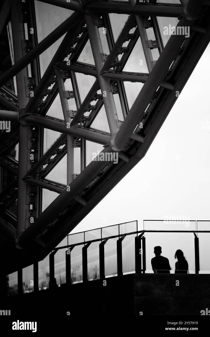 Couple walking under a metal structure Stock Photo - Alamy