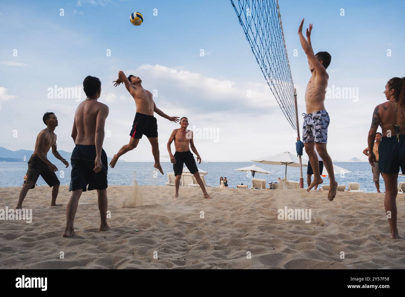 Multinational teams of people play beach volleyball on beach in summer ...
